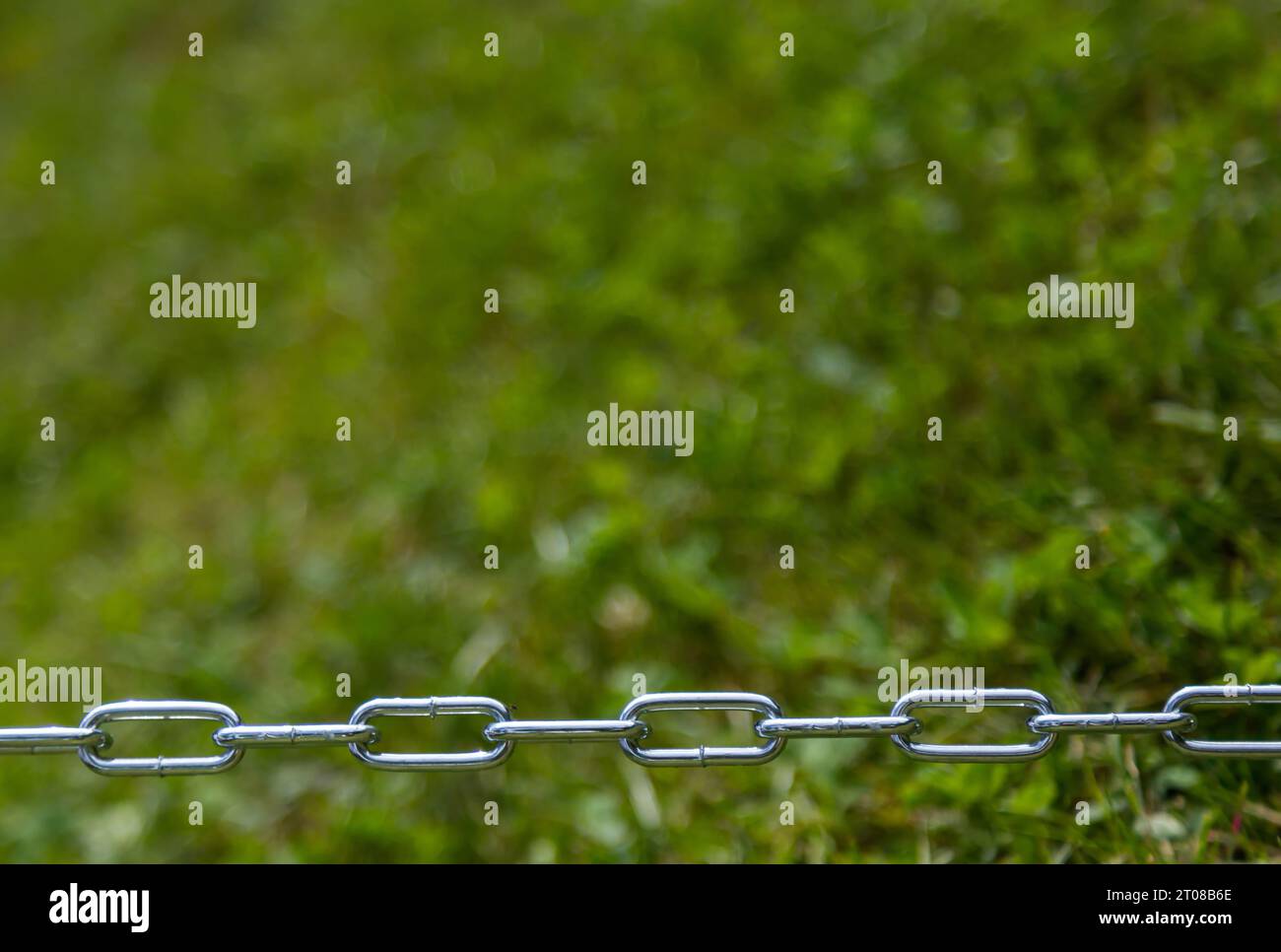 steel non-rusty chain on grass background, frame Stock Photo - Alamy