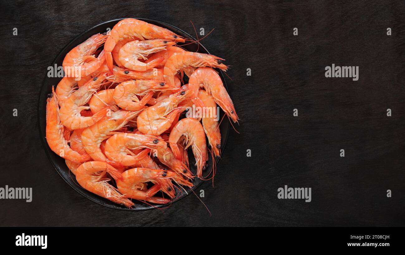 Boiled shrimp in a black plate on a dark wooden background. Fresh ...