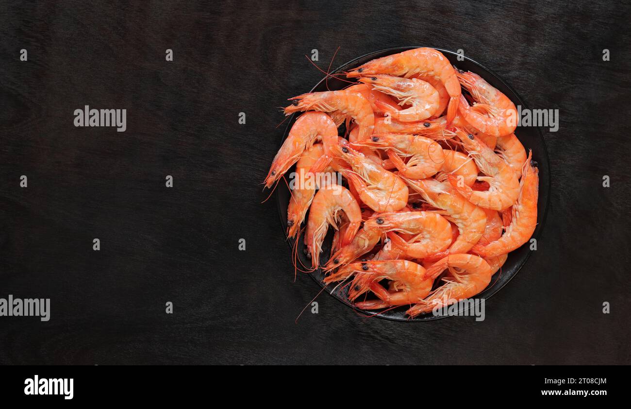 Boiled shrimp in a black plate on a dark wooden background. Fresh ...