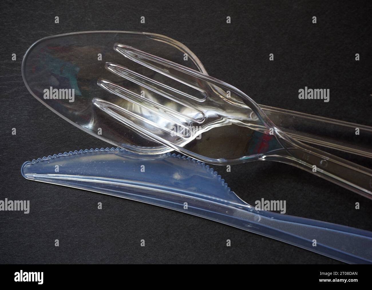 Single-Use plastic fork, spoon and knife on a black. Plastic cutlery ...