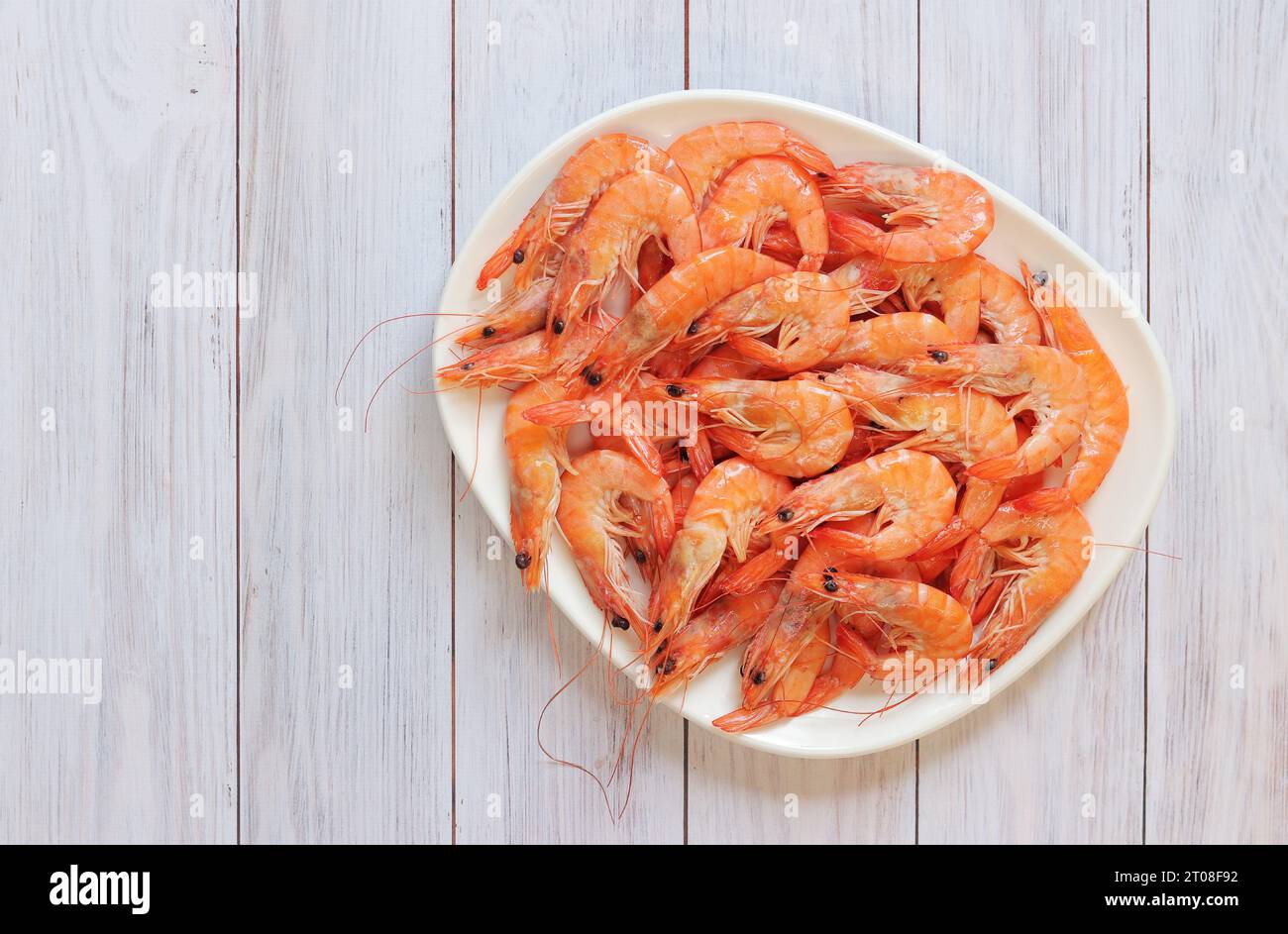 Boiled shrimp in a white plate on a light wooden background. Fresh ...