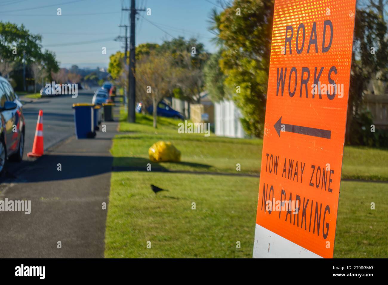 Orange board with Road Work sign on the side of the road. Cars and ...