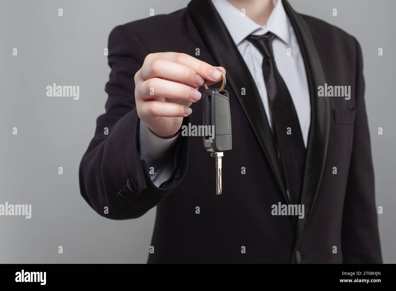 Human hand holding a car key on grey background. New car concept Stock ...