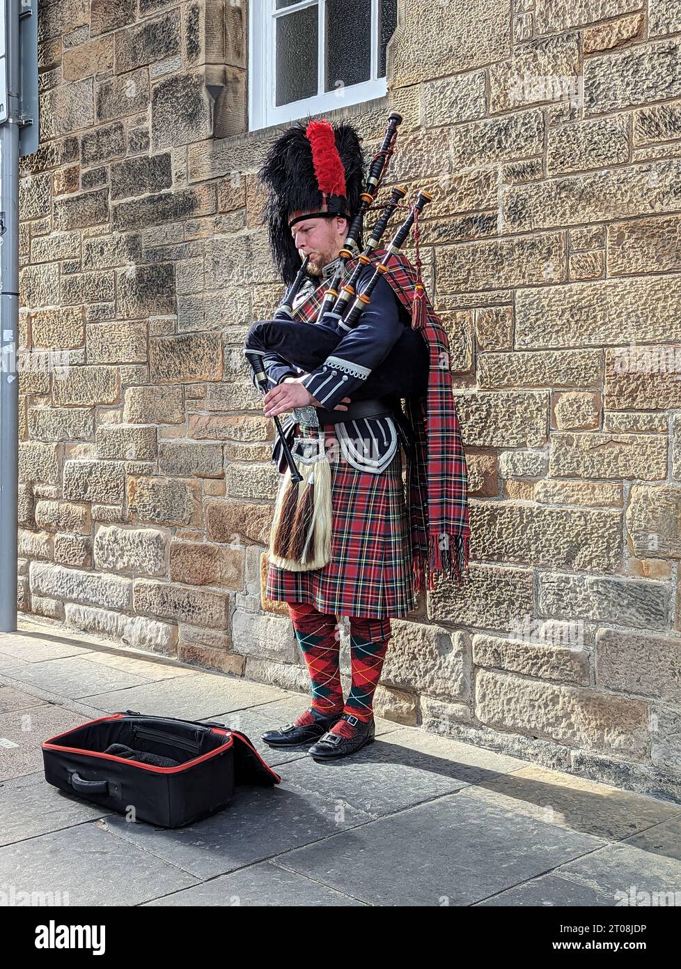 A man wearing traditional Scottish attire, playing a bagpipe on the ...