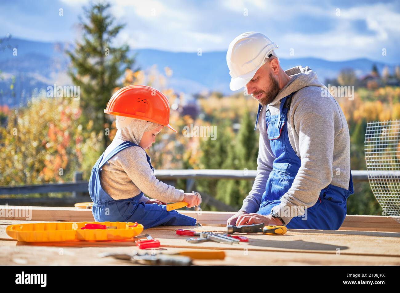 Father with toddler son building wooden frame house. Boy helping his ...