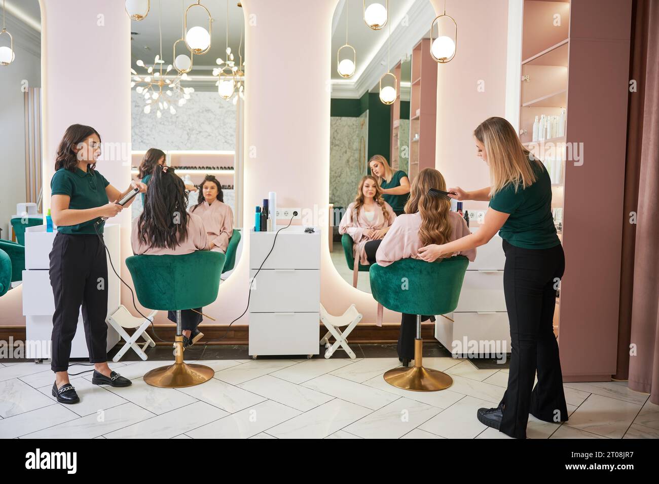 Two female hairstylists curling client hair and doing hairstyle in ...