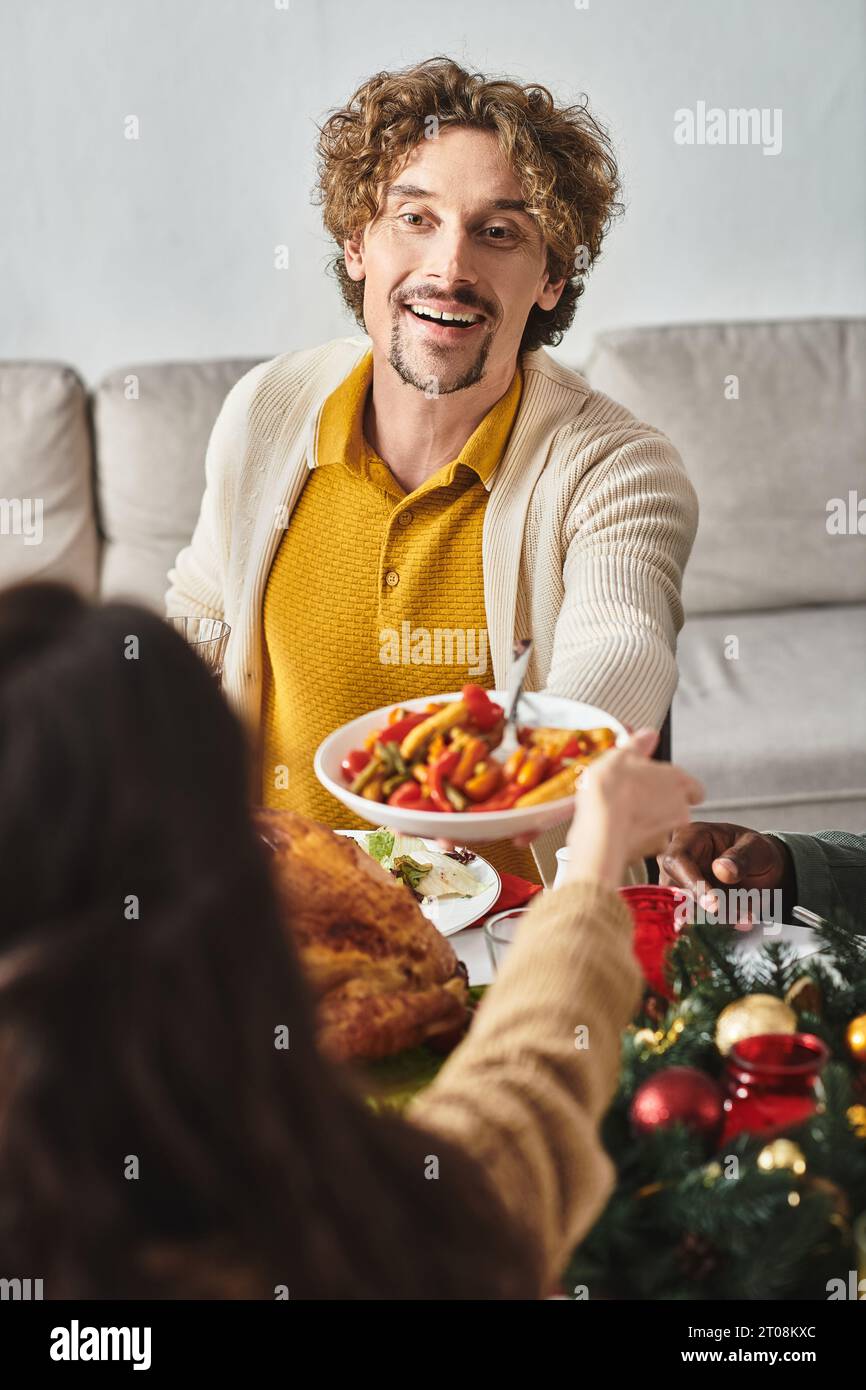 jolly man surrounded by his family at holiday lunch enjoying and sharing festive food, Christmas ...