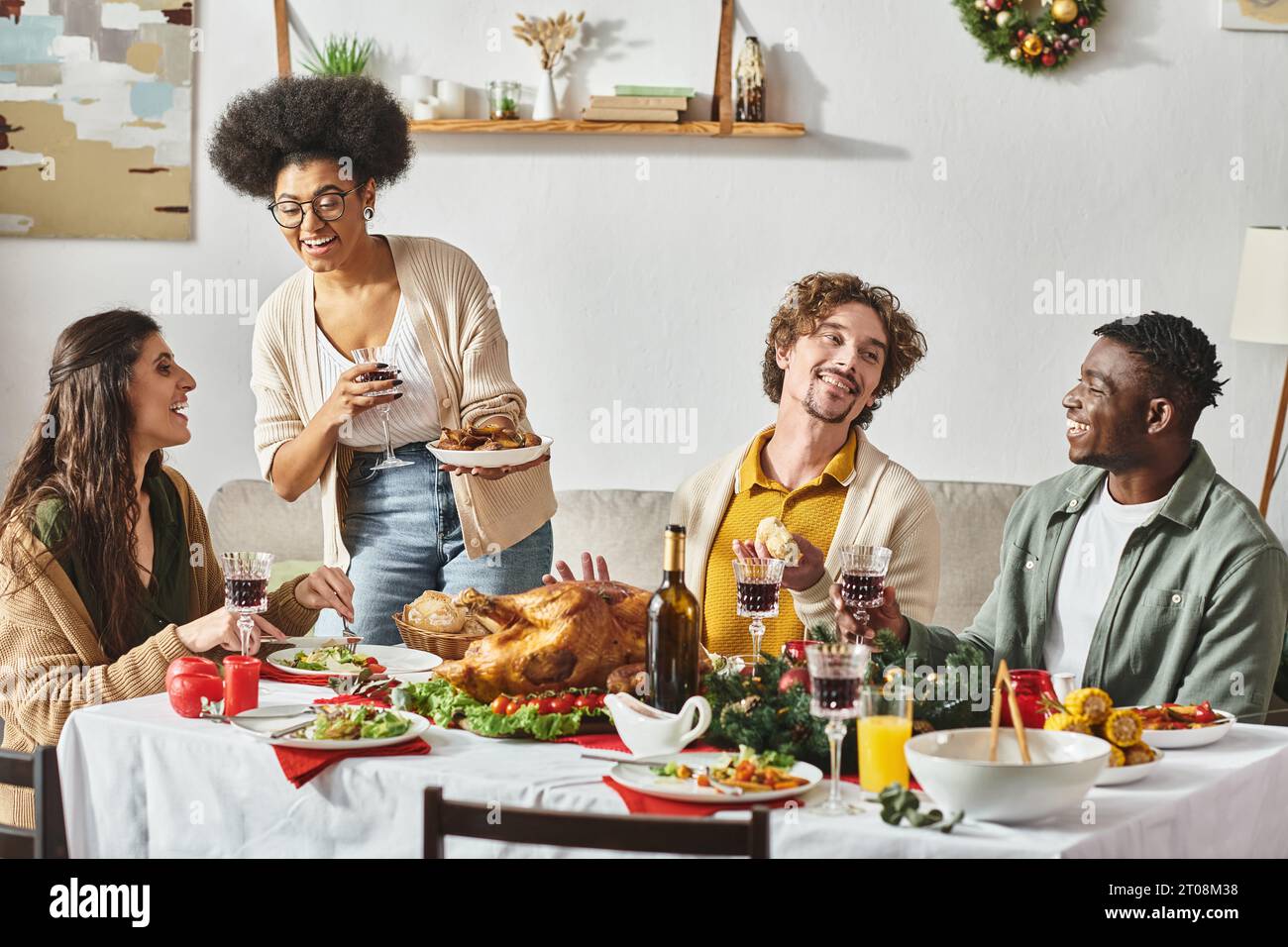big multicultural family sitting at Christmas table enjoying wine and ...