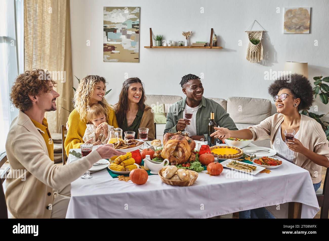 happy man passing plate with roasted potatoes to african american woman ...