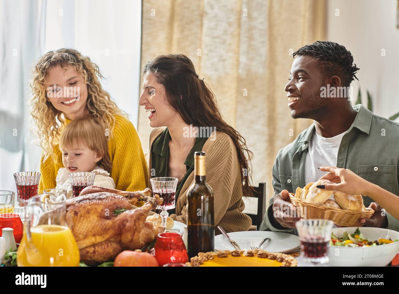 roasted turkey in center of table, happy interracial family celebrating ...