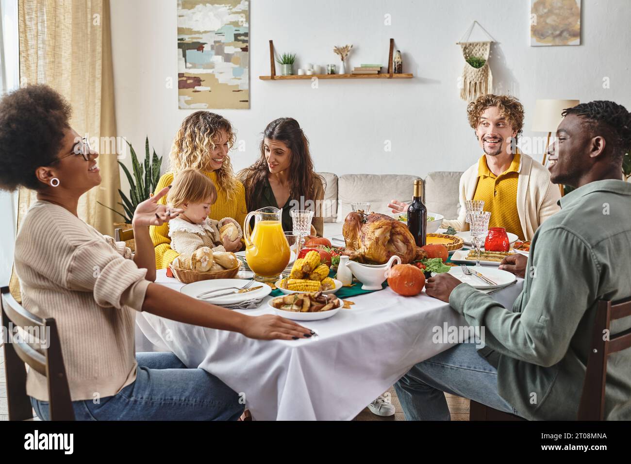 happy multiracial family and friends talking and smiling during ...
