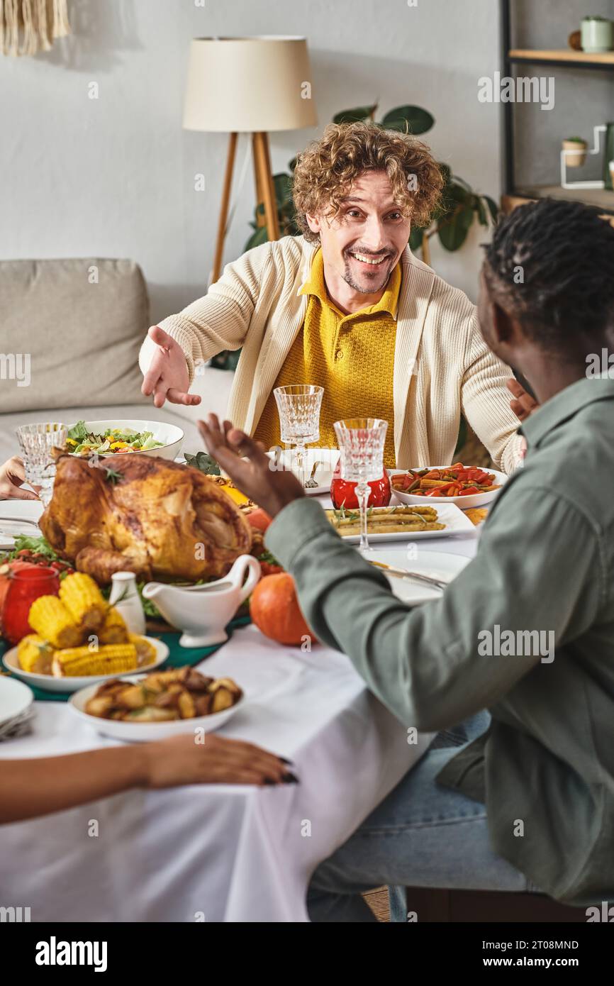 happy multicultural men talking near roasted turkey on Thanksgiving day ...
