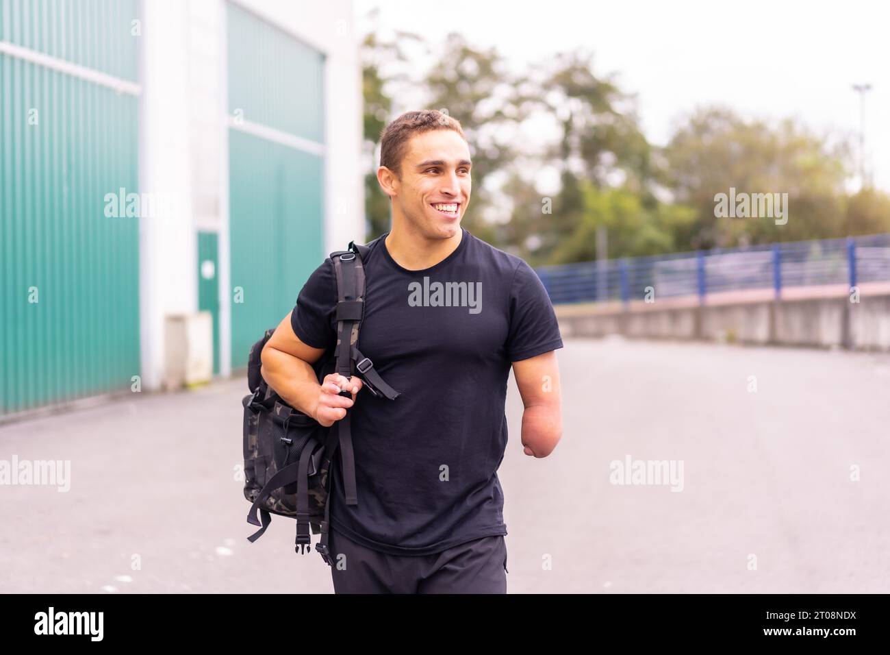 Happy and young athlete with one arm amputated arriving at the gym ...