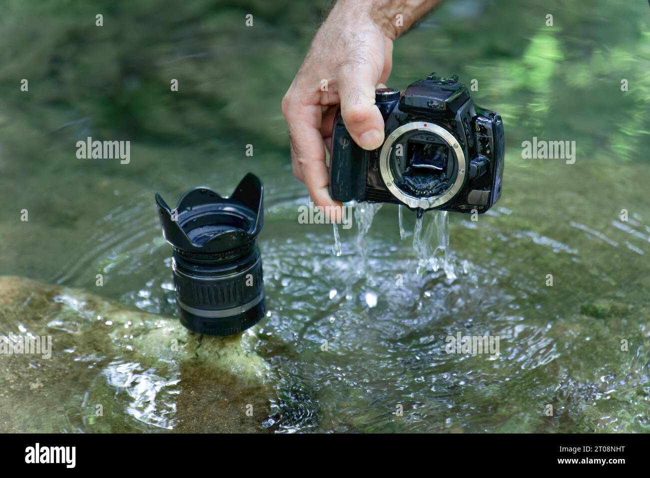 Man pulls his digital camera out of the river that has accidentally ...