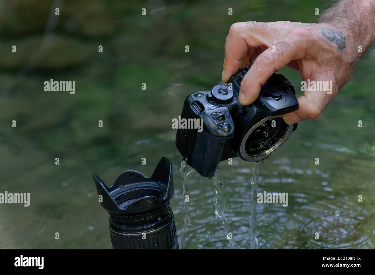 Man pulls his digital camera out of the river that has accidentally ...