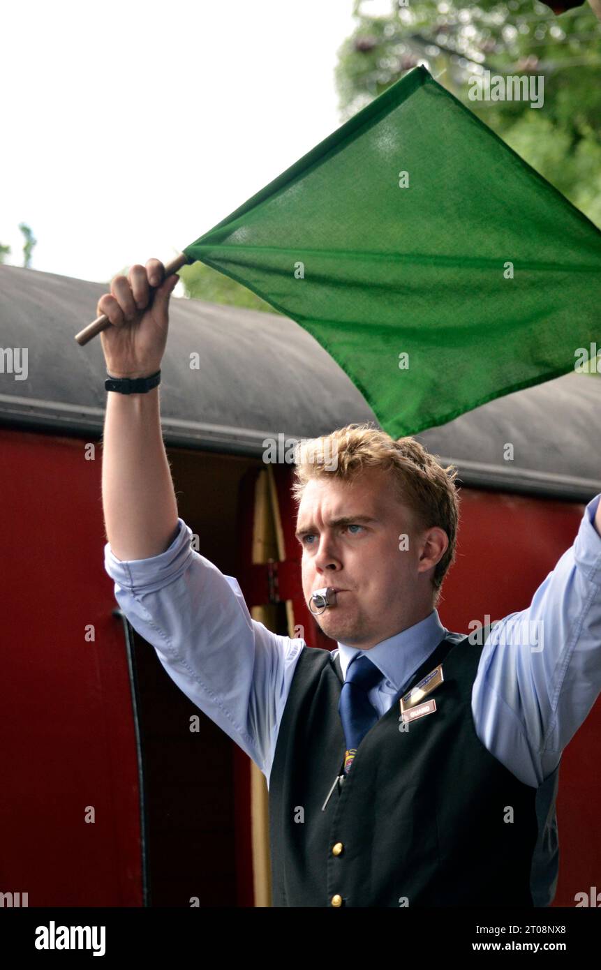 guard raises flag and blows whistle for train to depart, weybourne ...