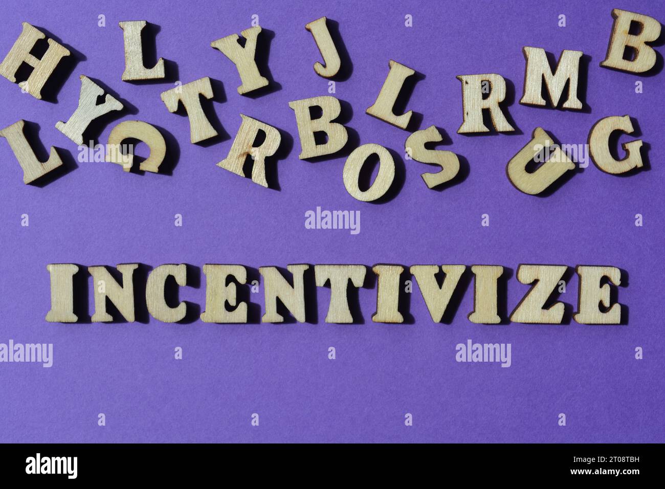 Incentivize, word in wooden alphabet letters isolated on purple ...