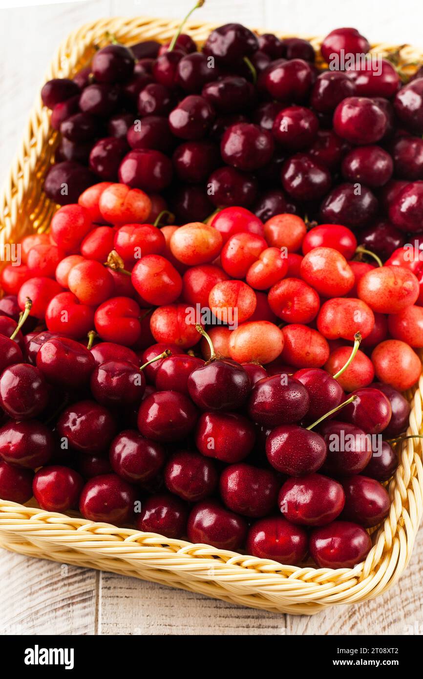 Ripe juicy cherries of different varieties in a wicker basket ...