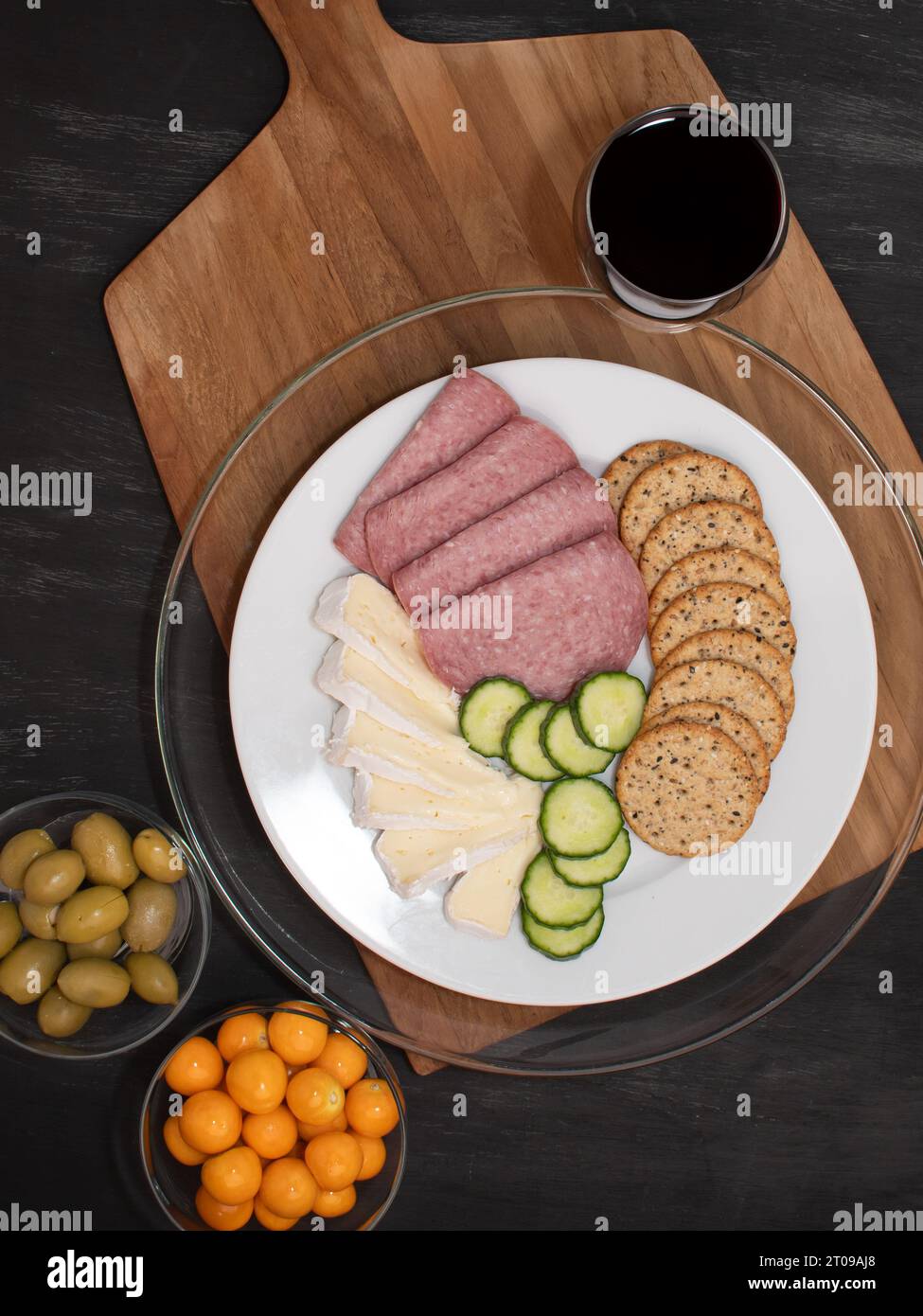 Top view of a simple, rustic table serving cheese, salami, and crackers ...