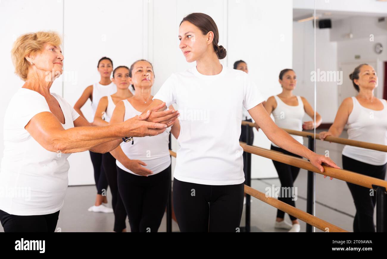 Dancing women stand in a ballet stance, where the choreographer helps ...