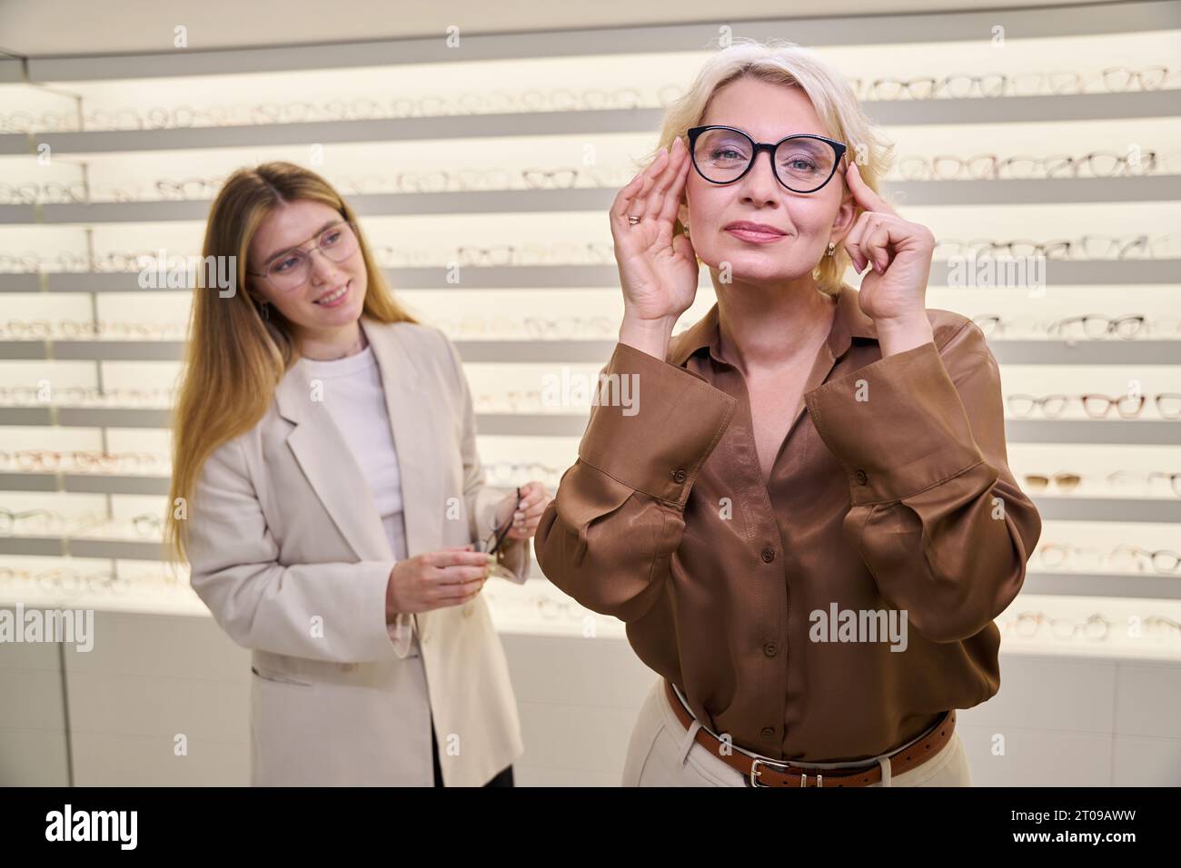 Charming middle-aged lady tries on glasses in an optical salon Stock ...
