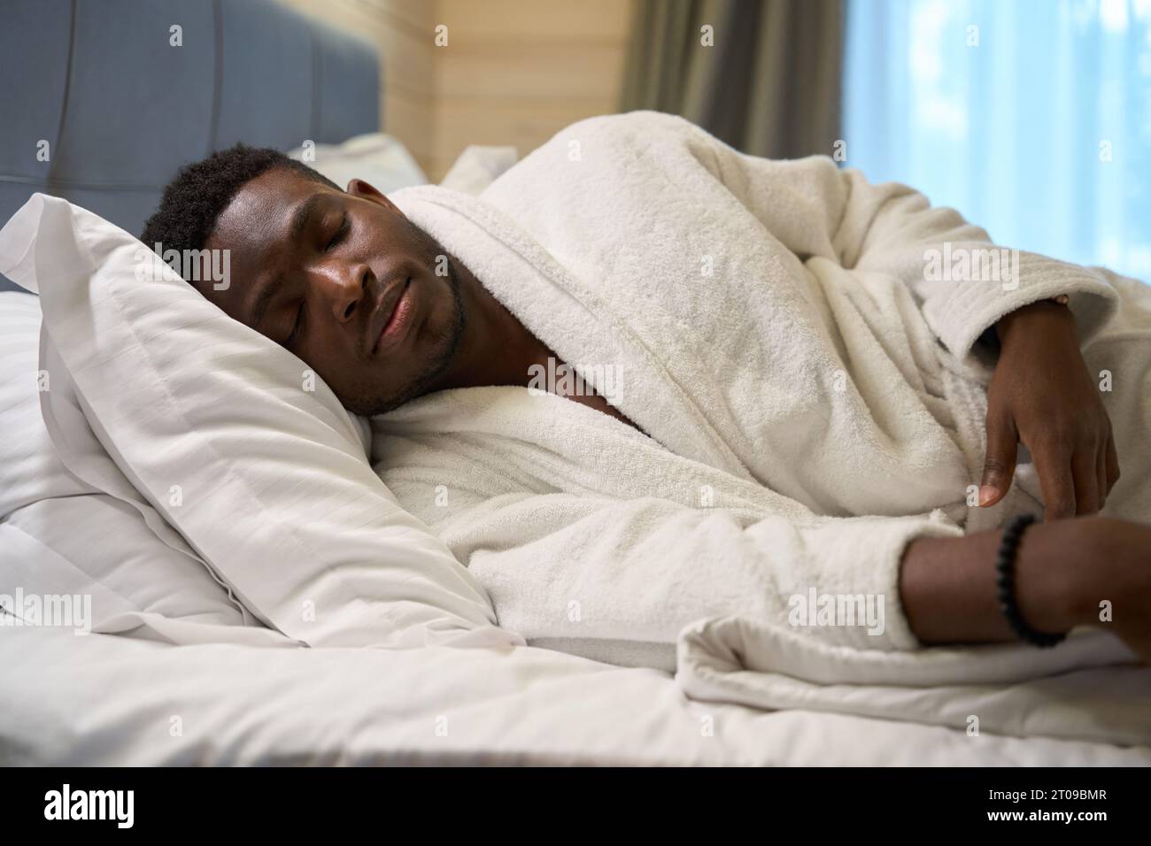 Man in terry robe fell asleep sweetly on large bed Stock Photo - Alamy
