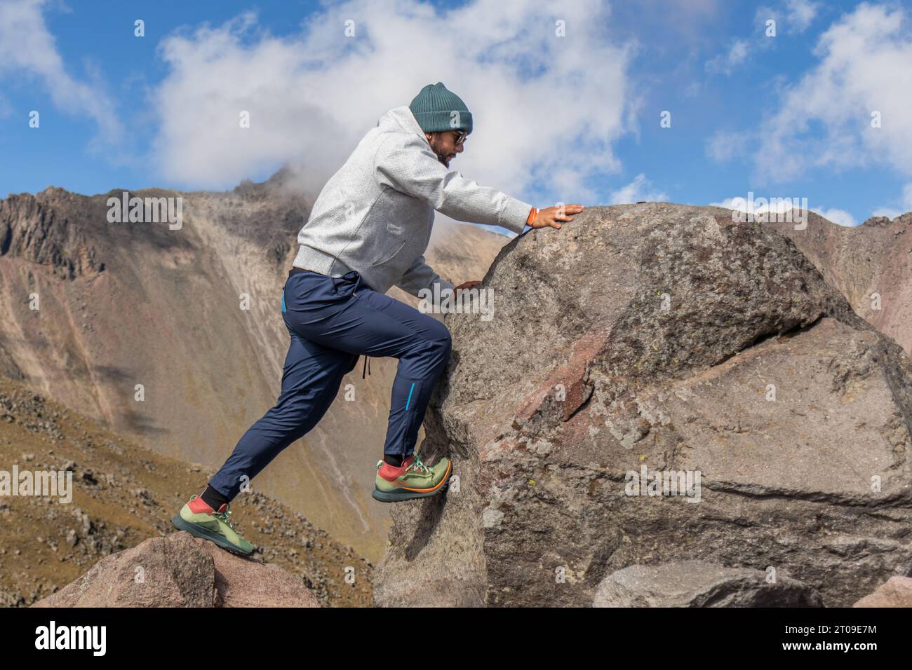 Full body side view of young male hiker looking down while climbing ...