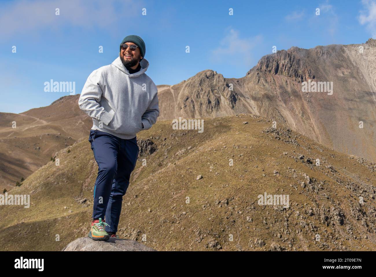Full body of young male hiker looking away while climbing huge boulder ...
