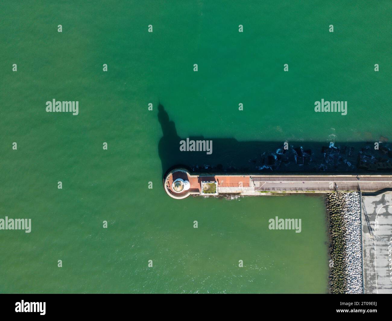 Aerial top down view of old stone lighthouse reflecting shadow on ...