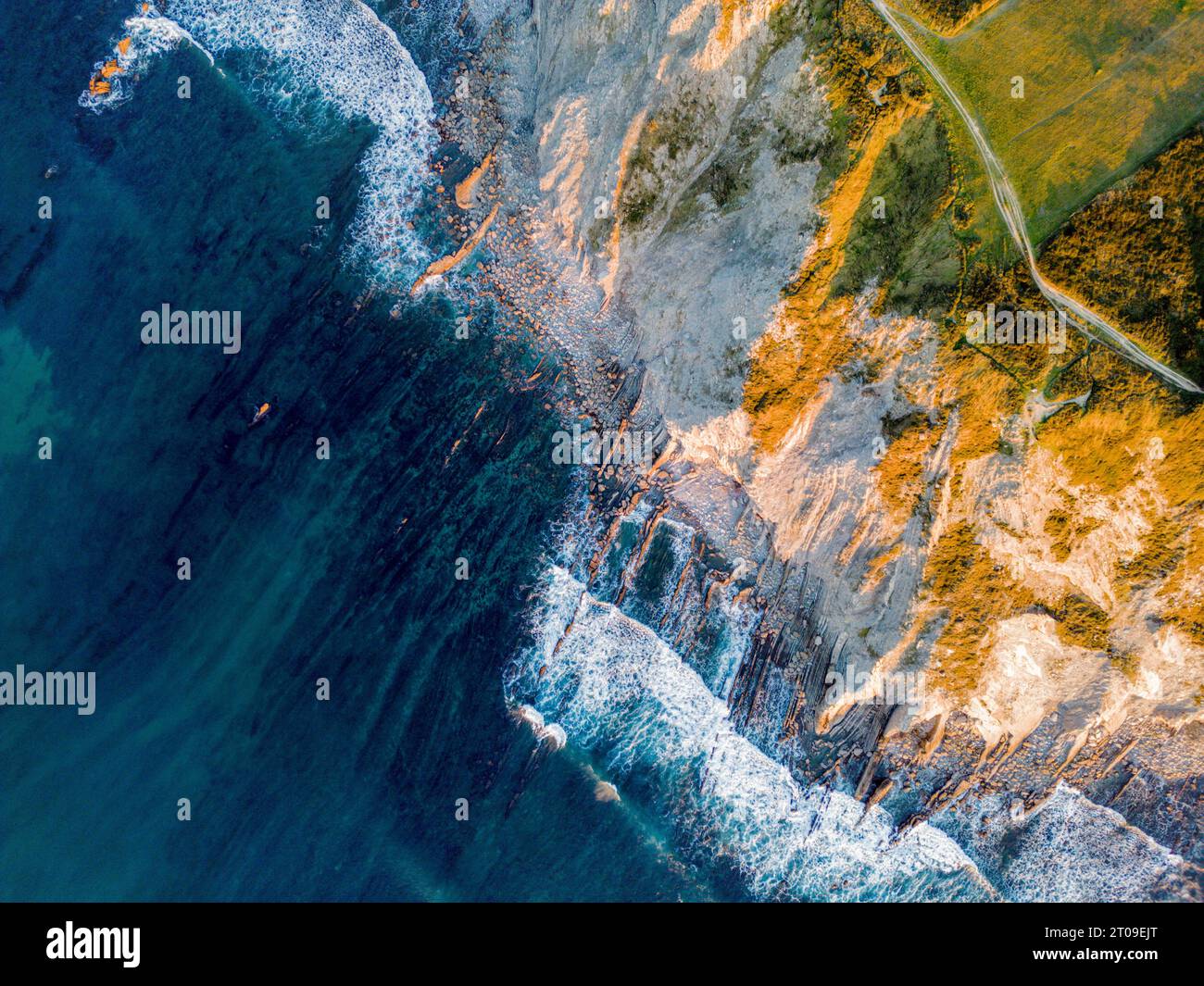 Aerial view of rough rocky cliff with uneven surface and blue ocean in ...