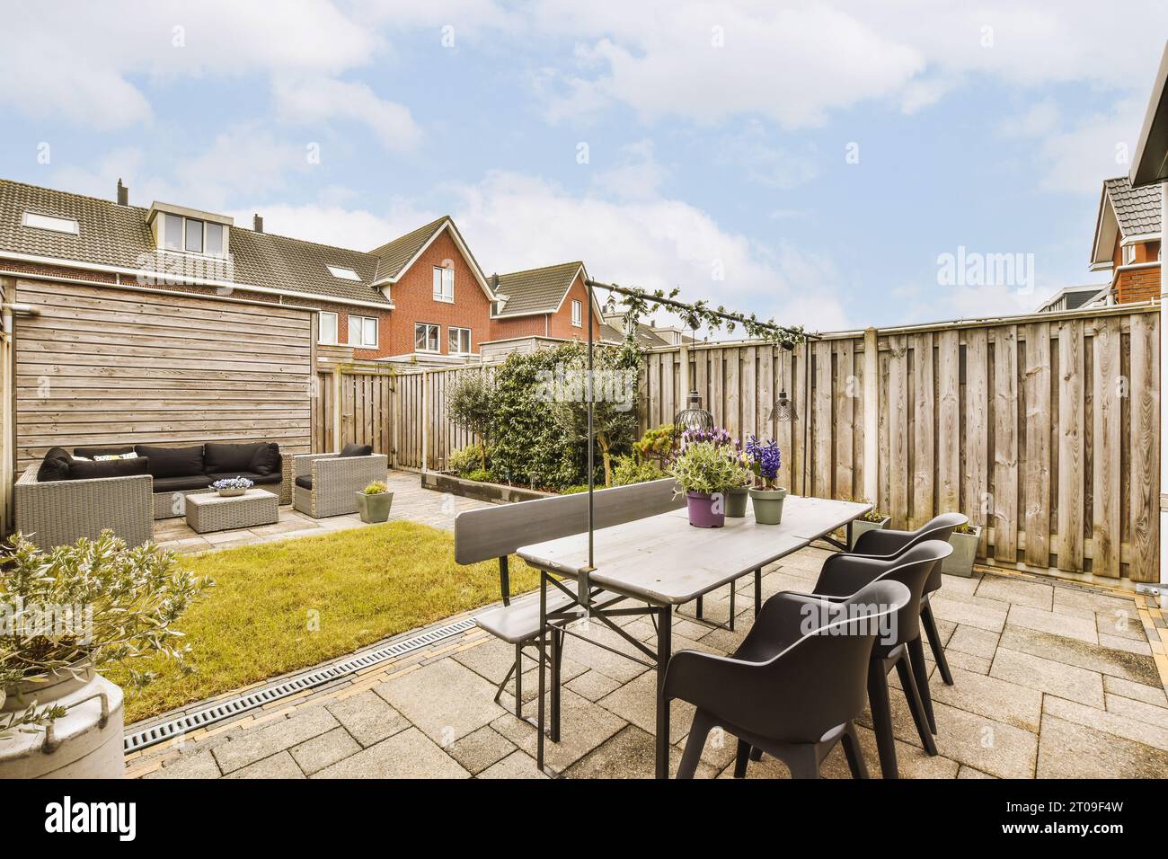 Spacious backyard area with table and empty chairs by small garden and ...