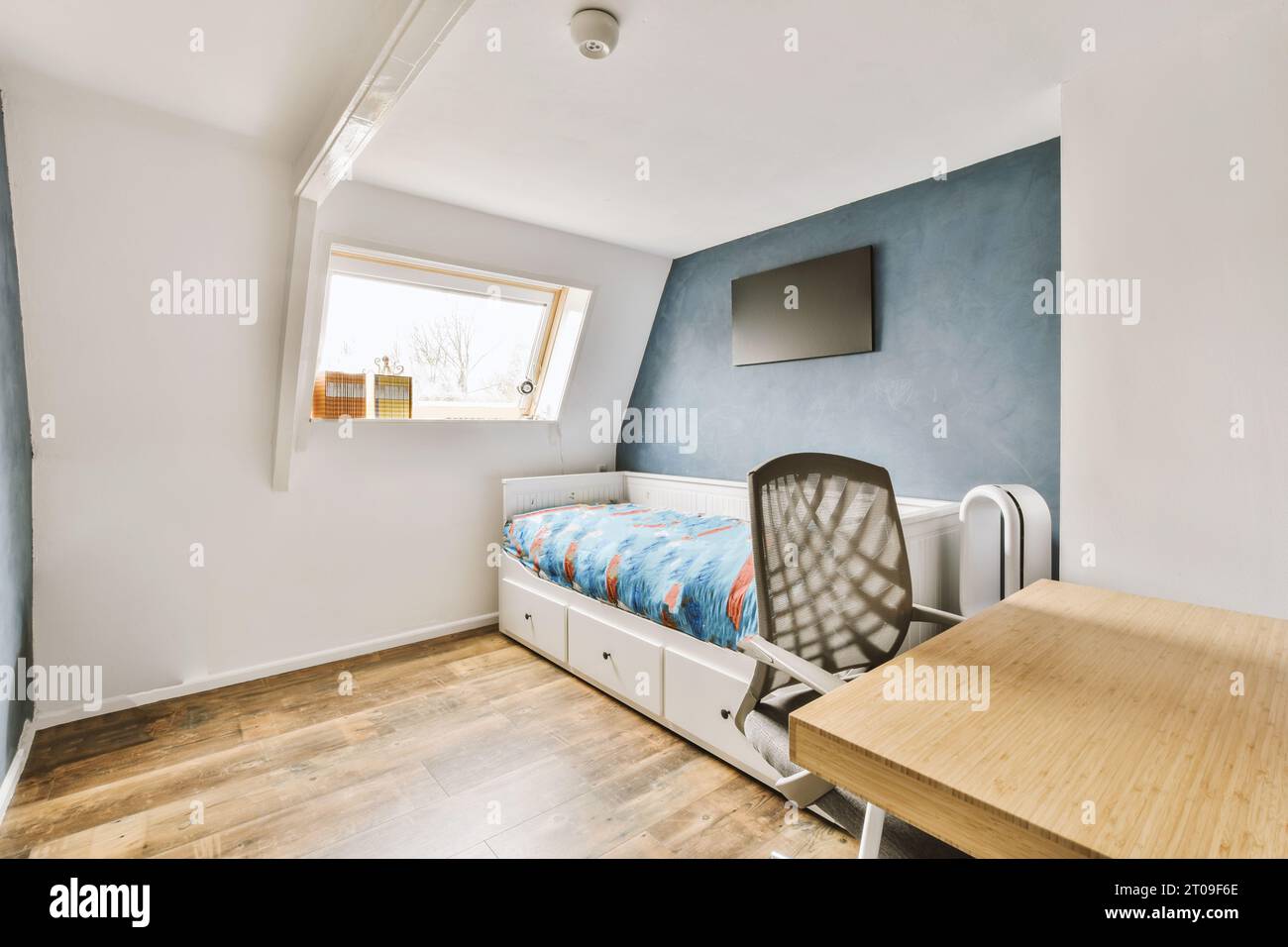 Interior of bedroom with chair and wooden desk by bed next to window in ...