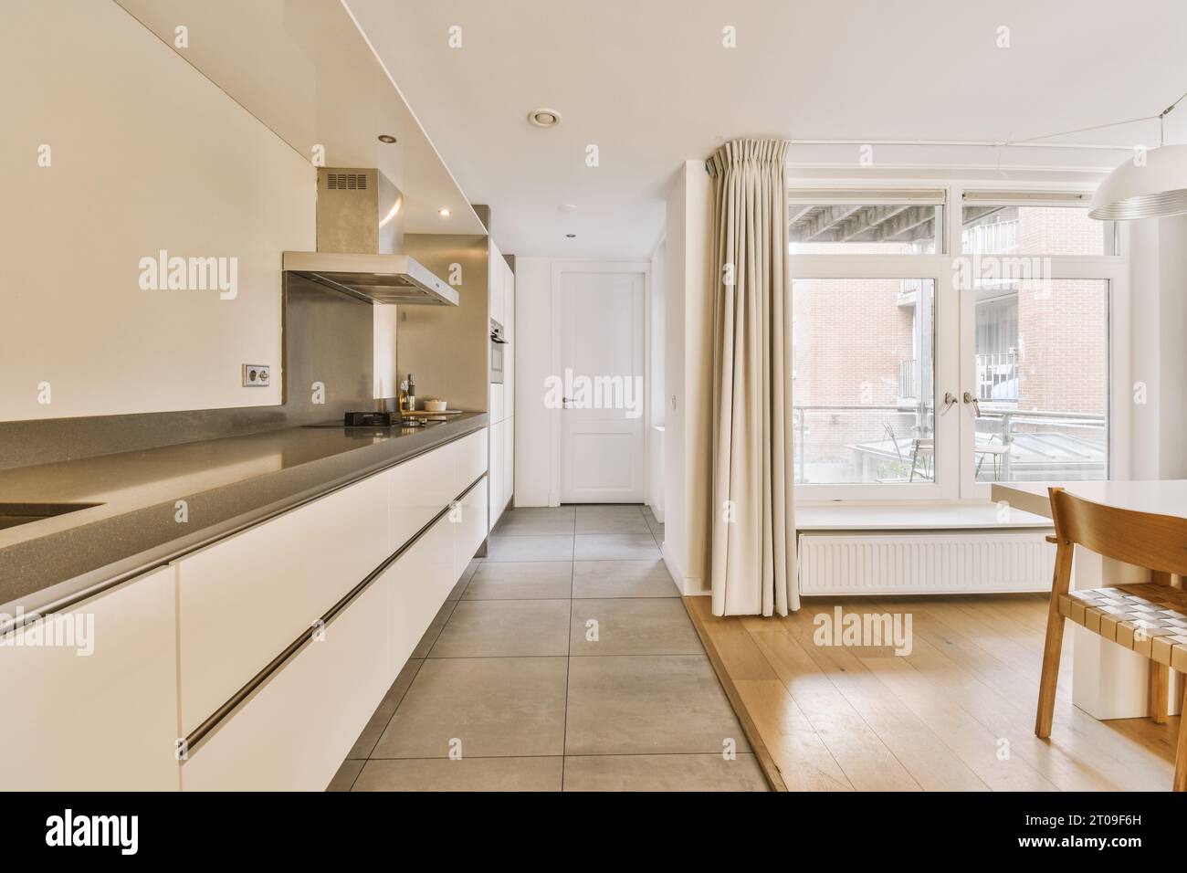 Modern open plan kitchen with long countertop with stove and rangehood ...