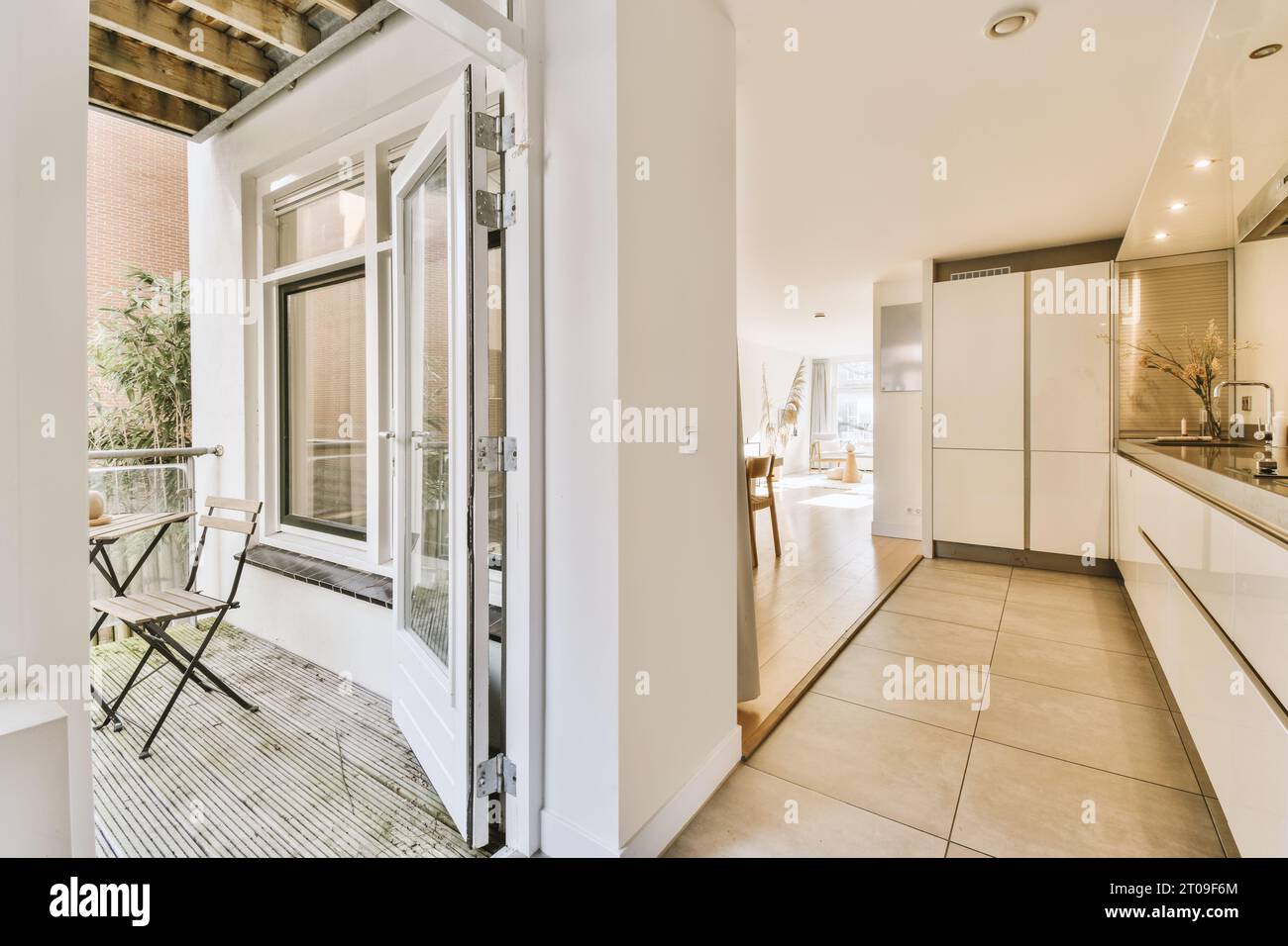 Passageway with open door by open plan illuminated kitchen in new ...
