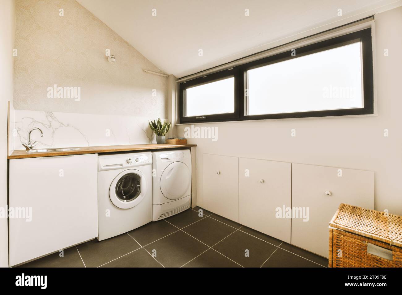 Interior of laundry room with white washing machine by window at modern ...