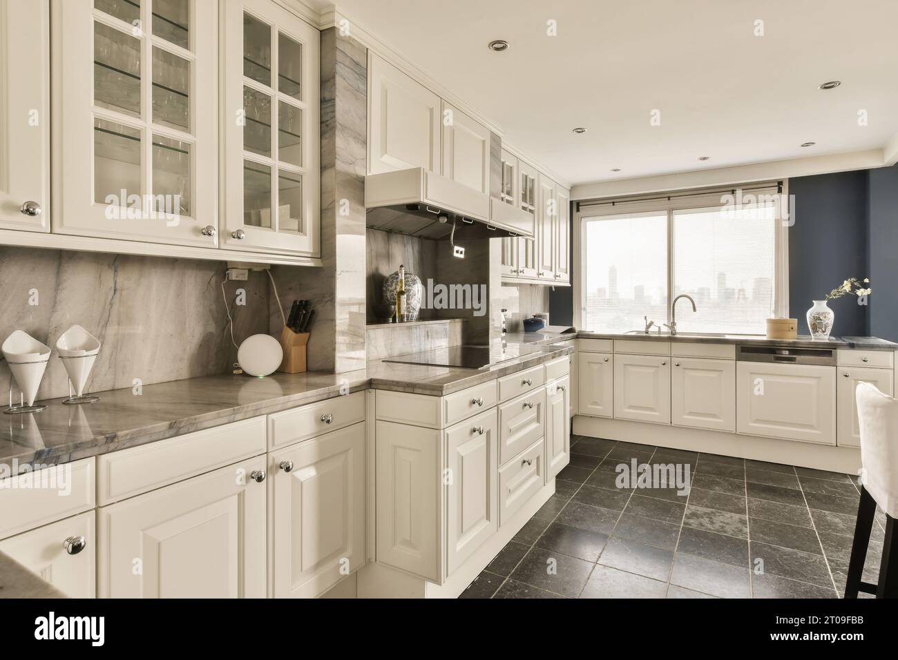 Interior of modern kitchen with marble countertops and white cabinets ...