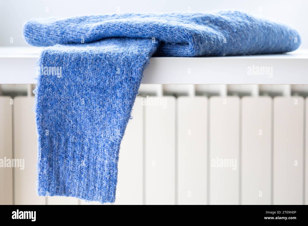 Blue wool sweater drying on a radiator in winter at home. Heating ...