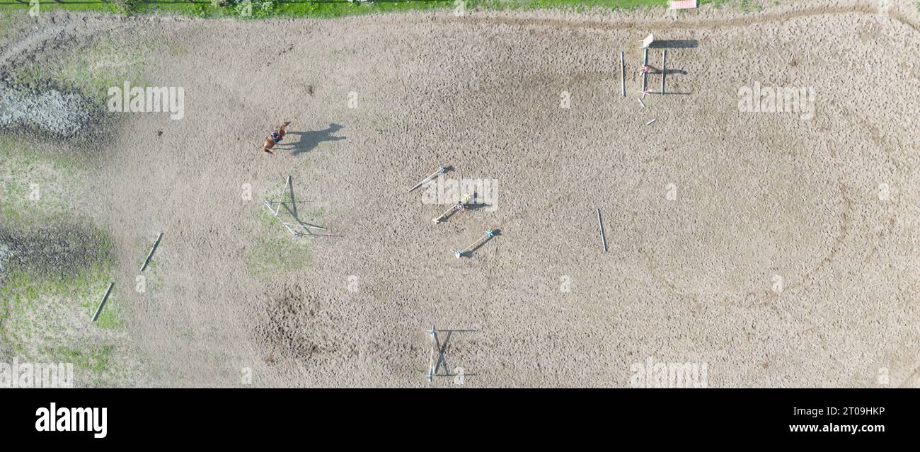 Aerial view of three horsemen. A riding field with fence and obstacles ...