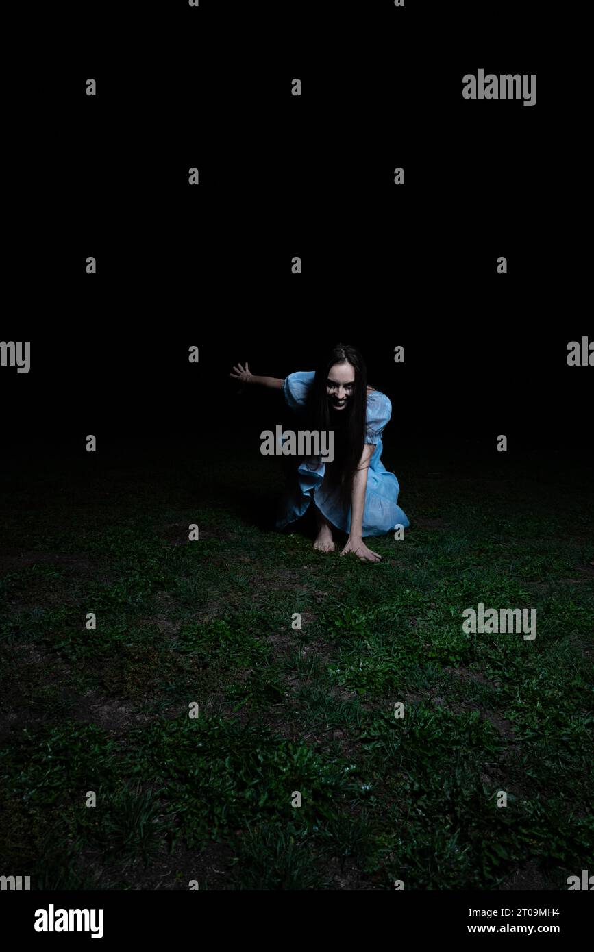 a scary girl in a blue dress is standing in the dark.a terrible drowned ...
