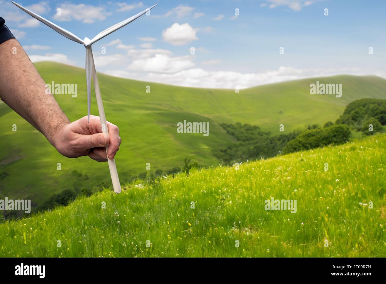 Hand places a wind turbine in a hilly landscape. Symbol for building ...
