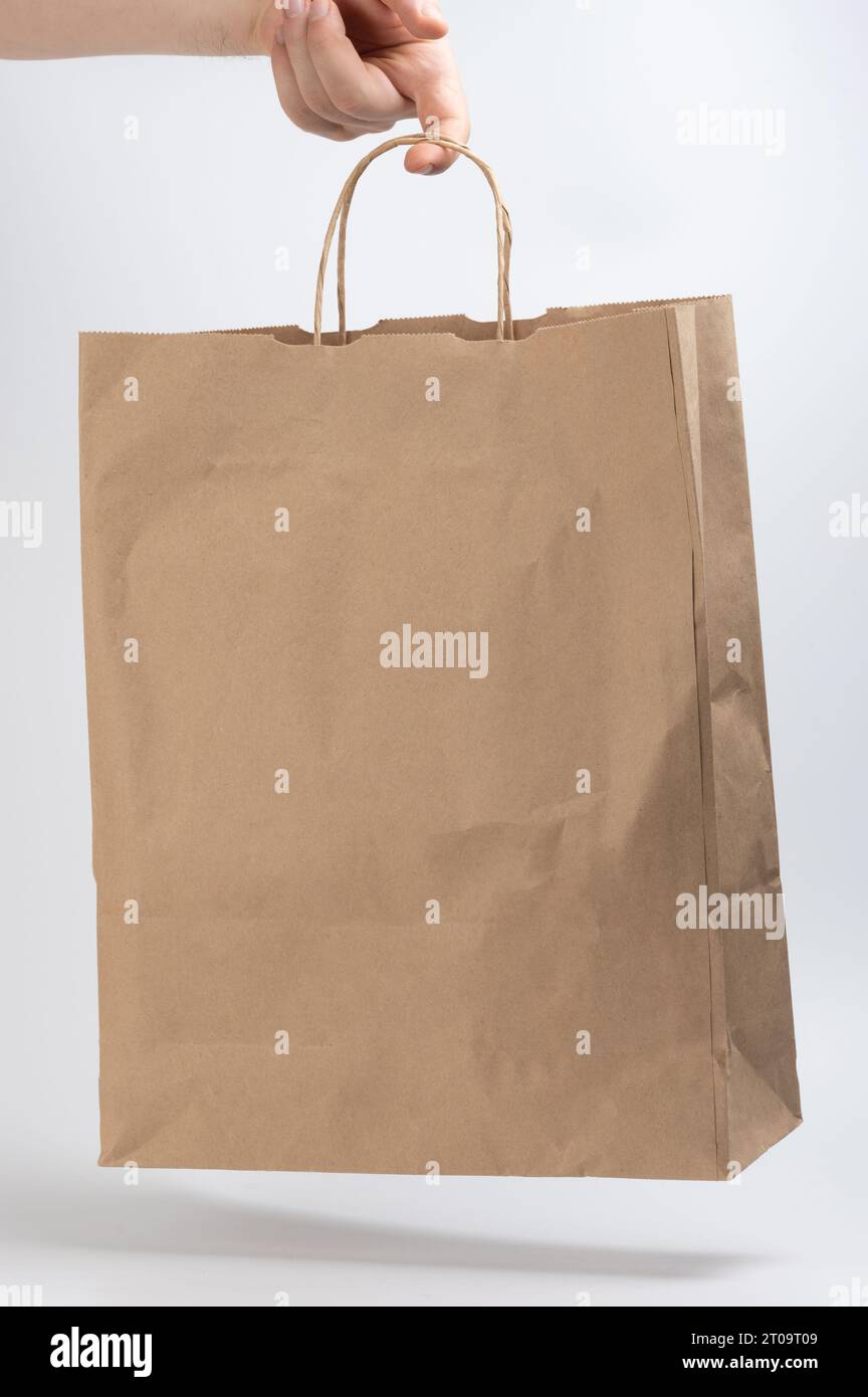 Brown paper bag in hand with handle isolated on white studio background ...