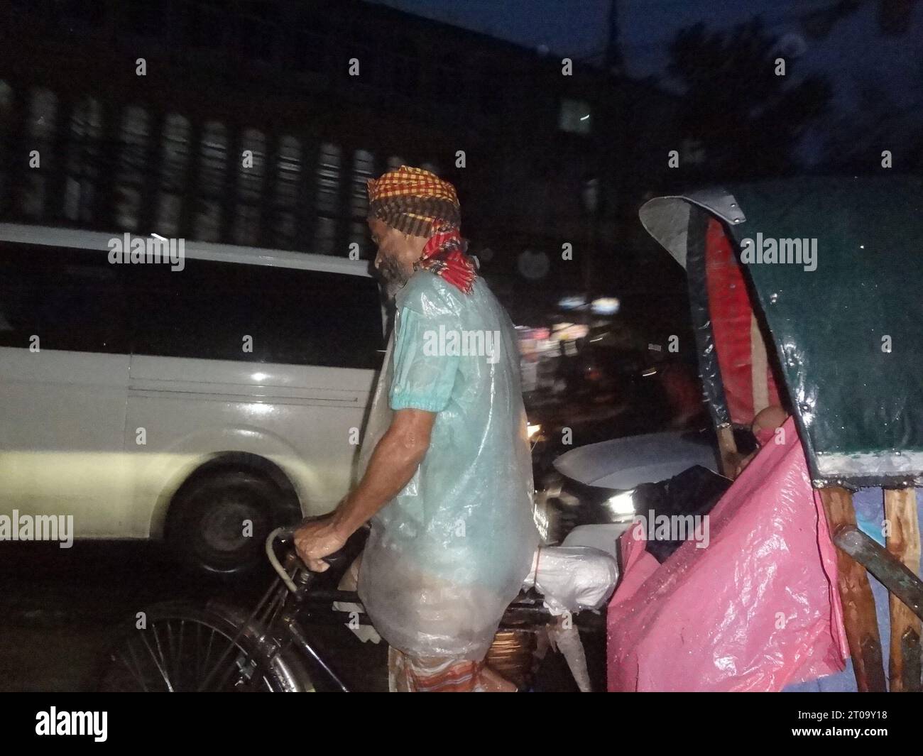 Dhaka, Bangladesh. 5th Oct, 2023. A rickshaw puller uses a plastic sheet to shield them from the ...