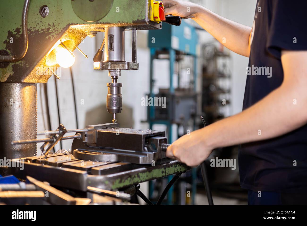 Worker drilling a steel piece with a professional industrial machine in ...