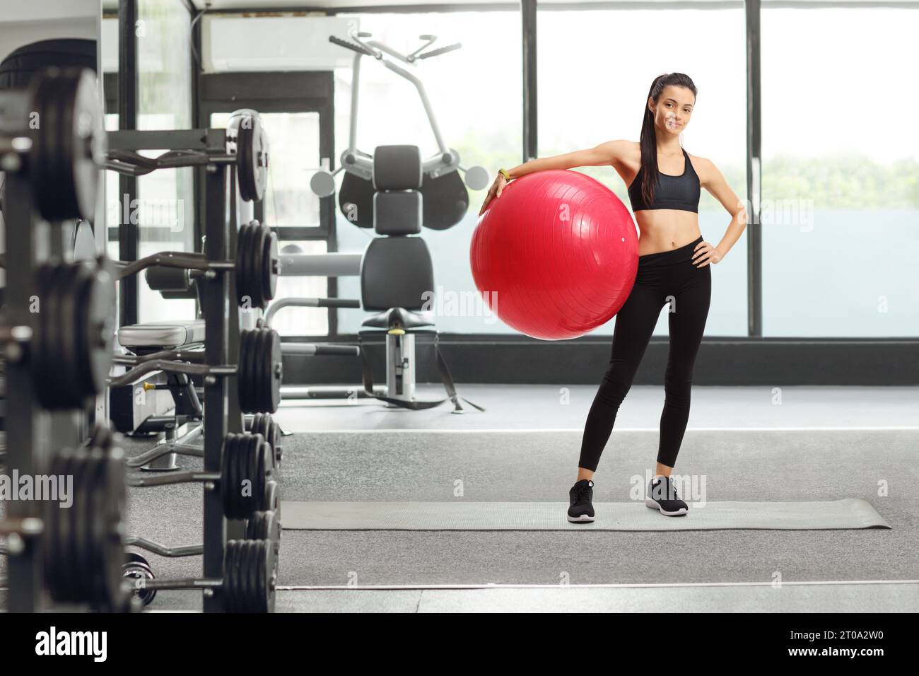 Full length portrait of a young female in sportswear holding a red ...