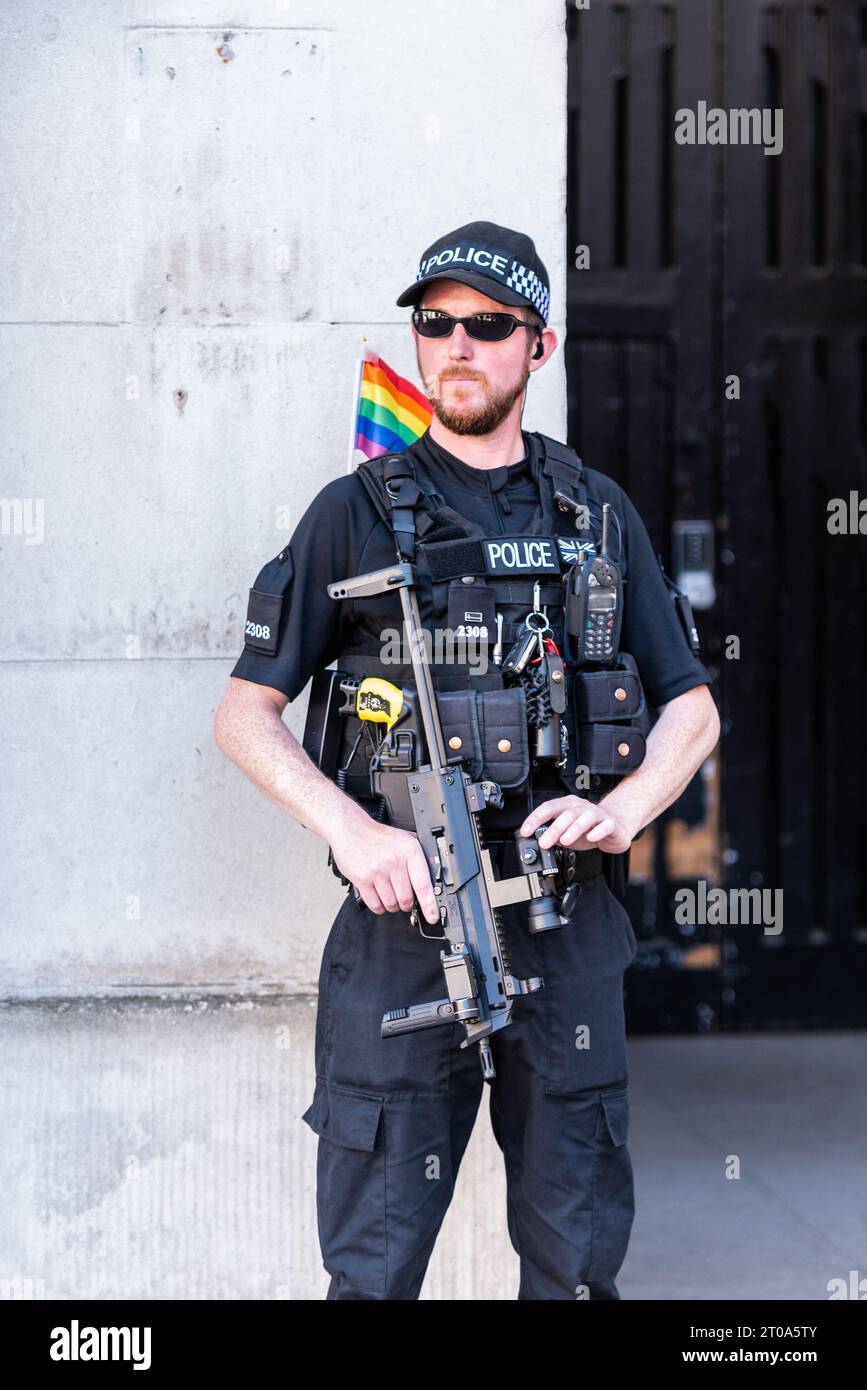 Armed police officer with rainbow colours flag. Male police officer ...