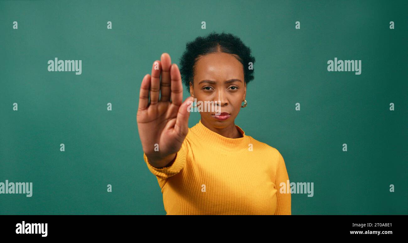 Young Black woman holds up hand saying No, Stop, green studio ...