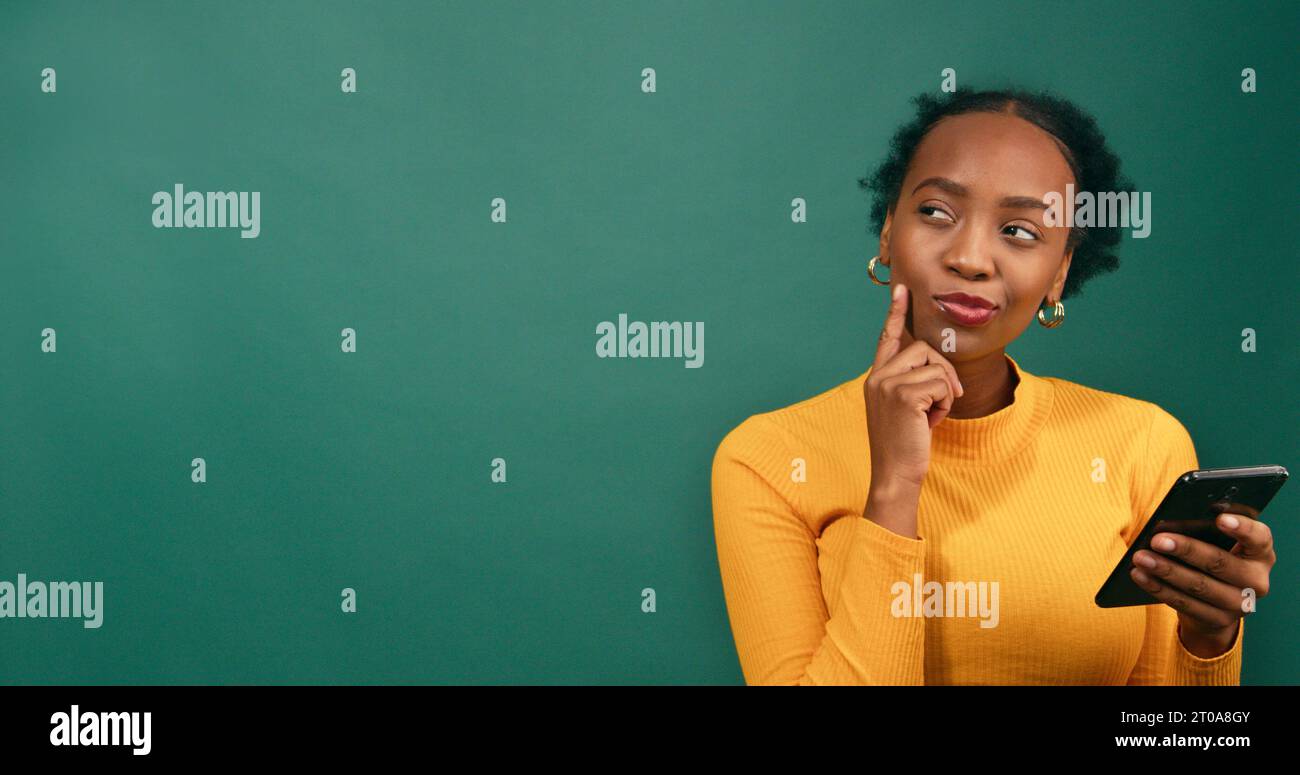 Young woman thinking has idea what to text, green studio background ...