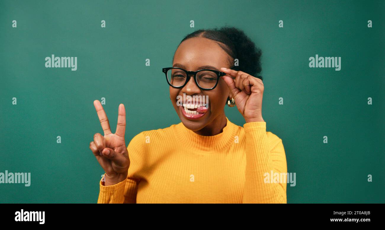Beautiful Black woman tries on eyeglasses, spectacles, green studio ...