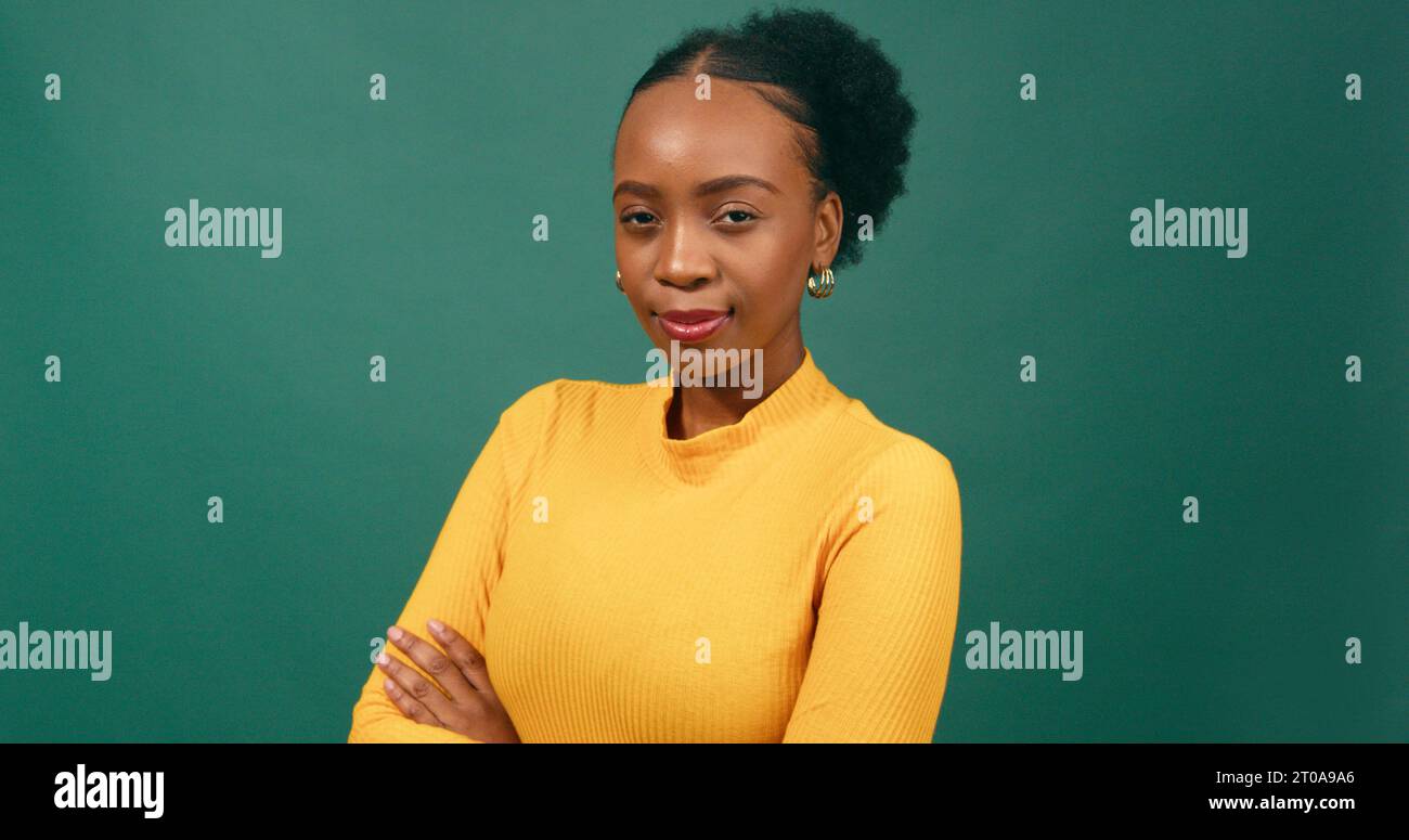 Beautiful Black woman folds arms serious portrait, green studio ...