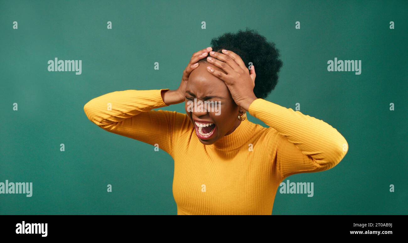 Frustrated and angry young woman hands in hair - green studio ...